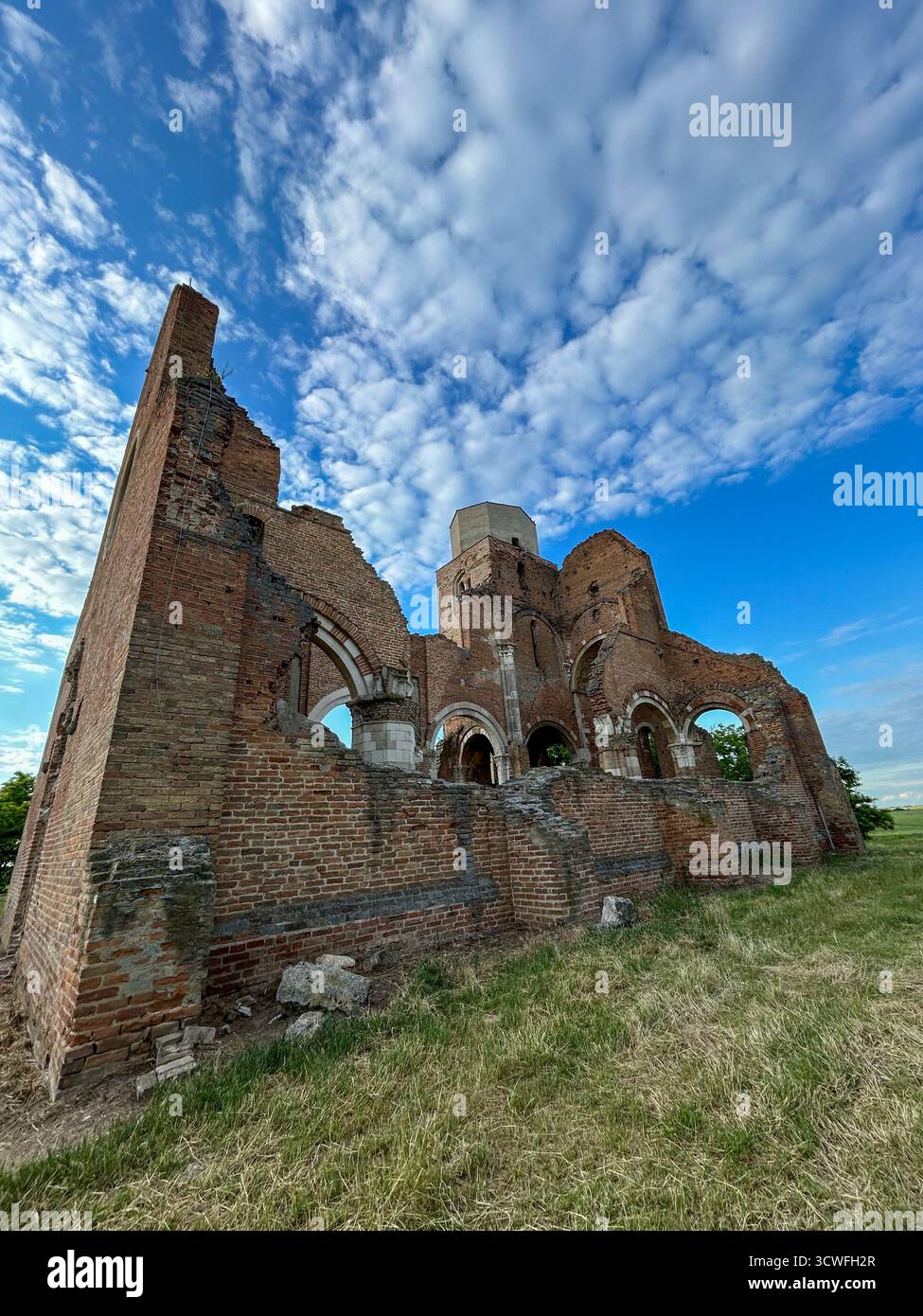 Remains of an old brick church with arches and tower under a bright ...