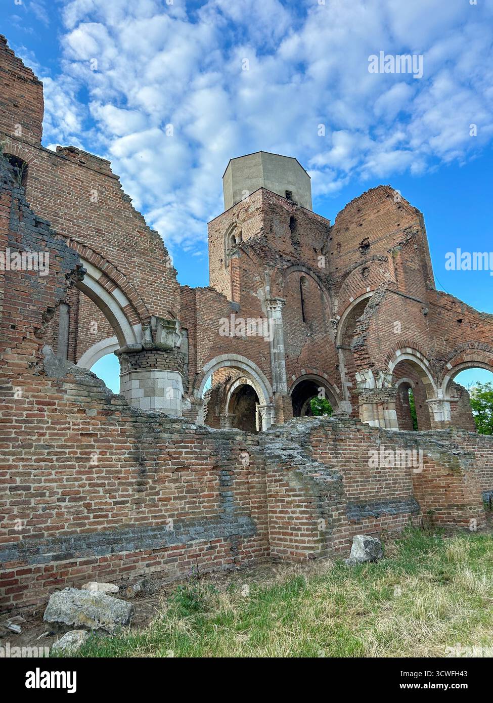 Historic brick church ruins standing on a grassy field under a vibrant ...