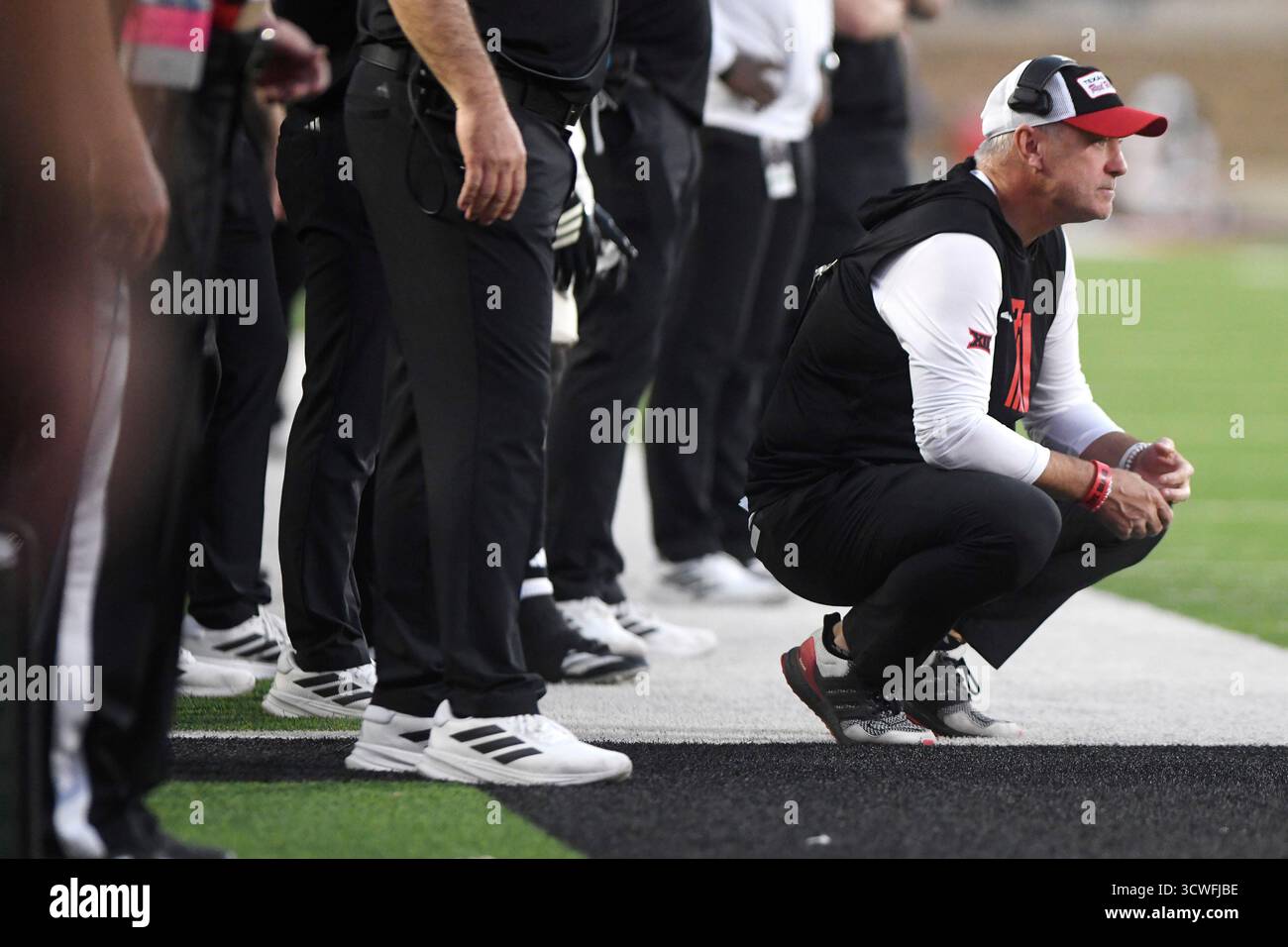 Texas Tech head coach Joey McGuire squats on the sidelines during the ...
