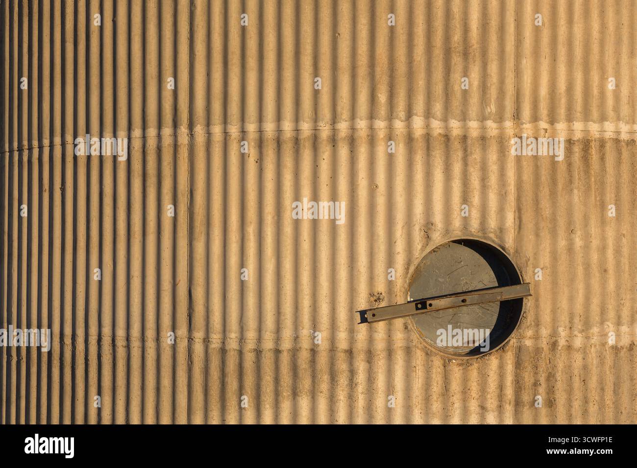 Corrugated concrete grain silo with a circular metal inspection hatch ...