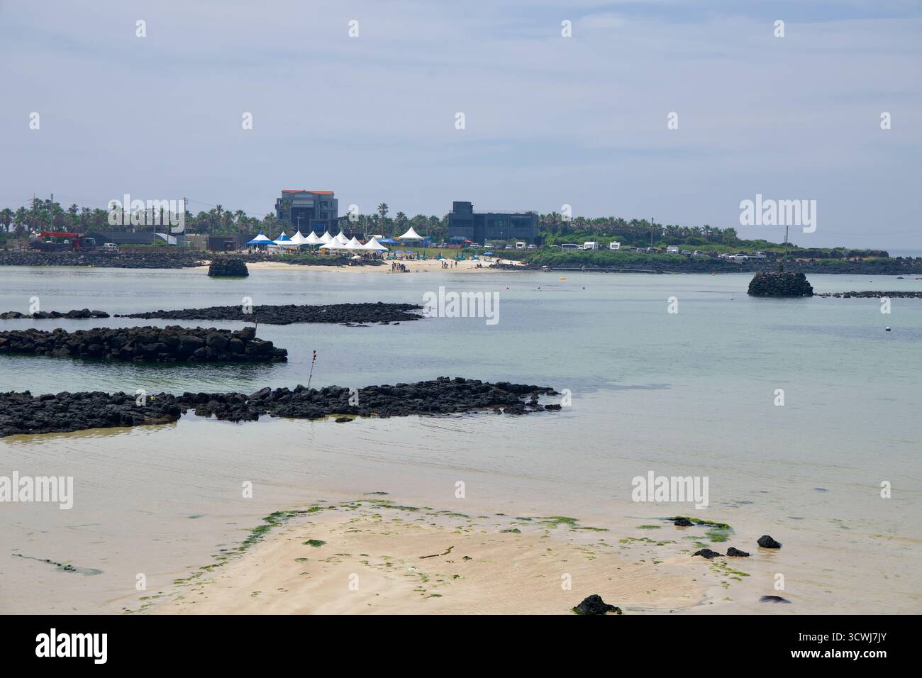 Across the lagoon from the lava reef, tents and beachgoers line ...