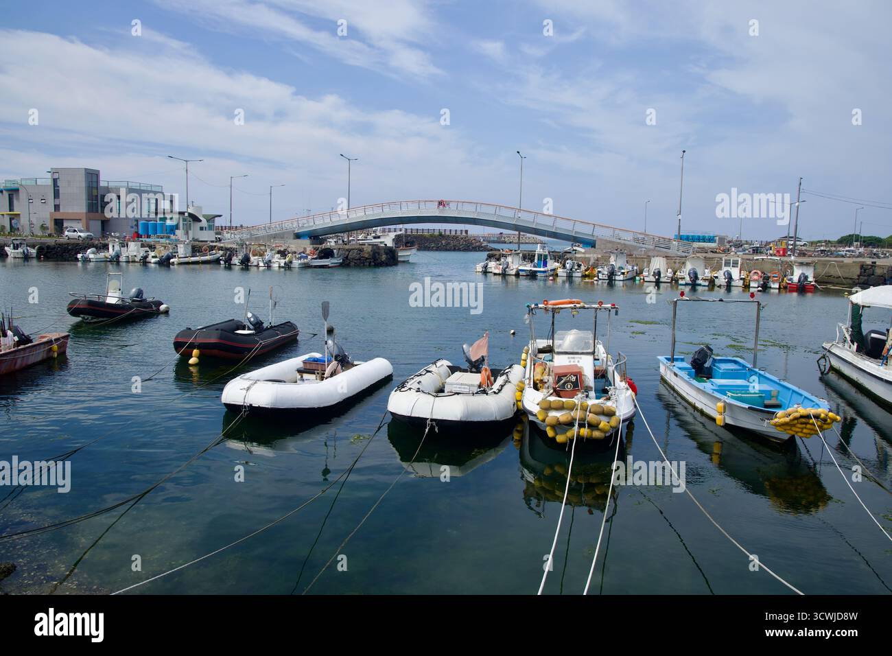 An arched pedestrian bridge crosses the harbor channel at Hwabuk as ...