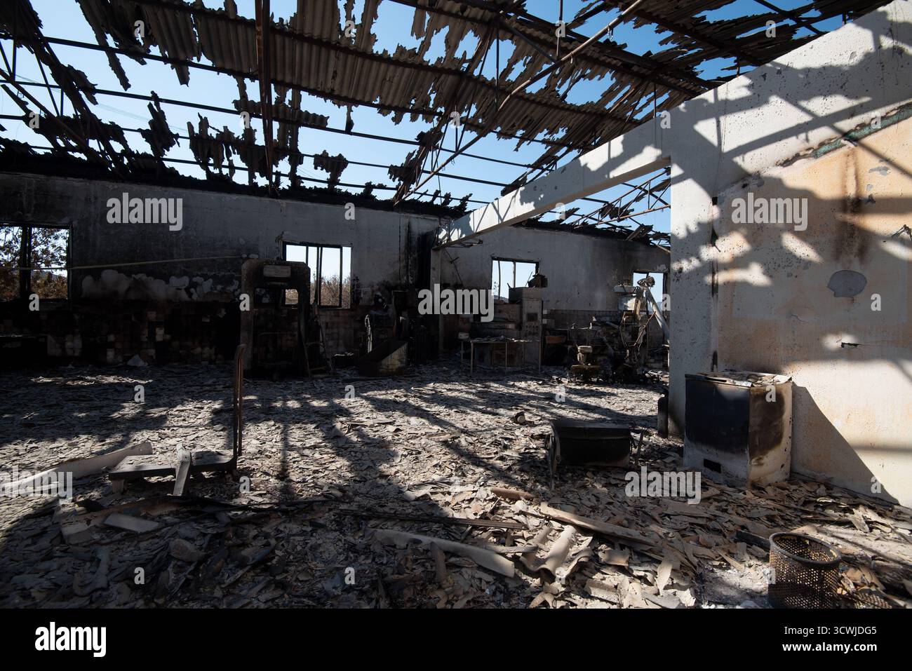 Charred remnants of a factory building reveal scattered debris and ...