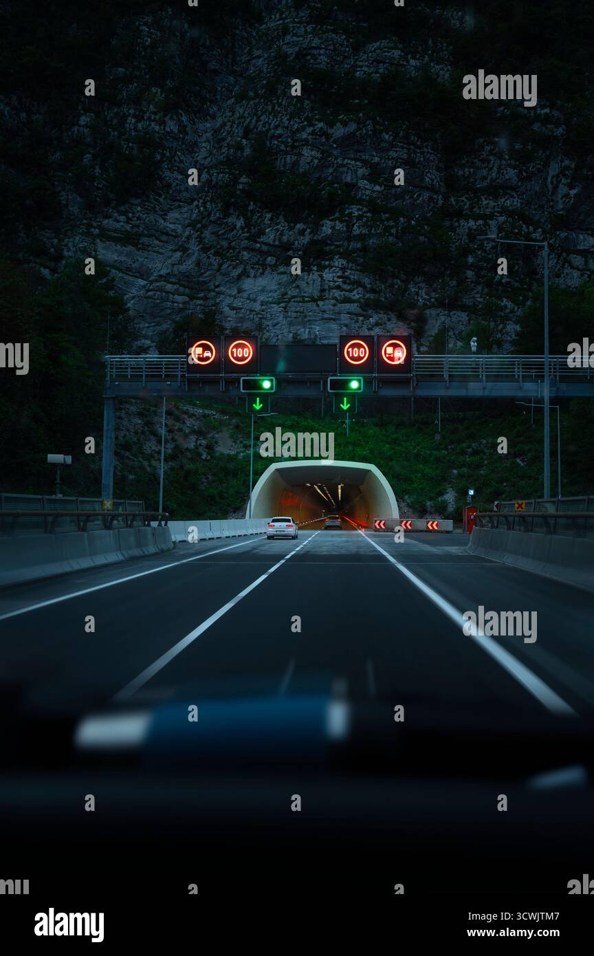 Highway tunnel with light signals, speed limit, and warning signs ...