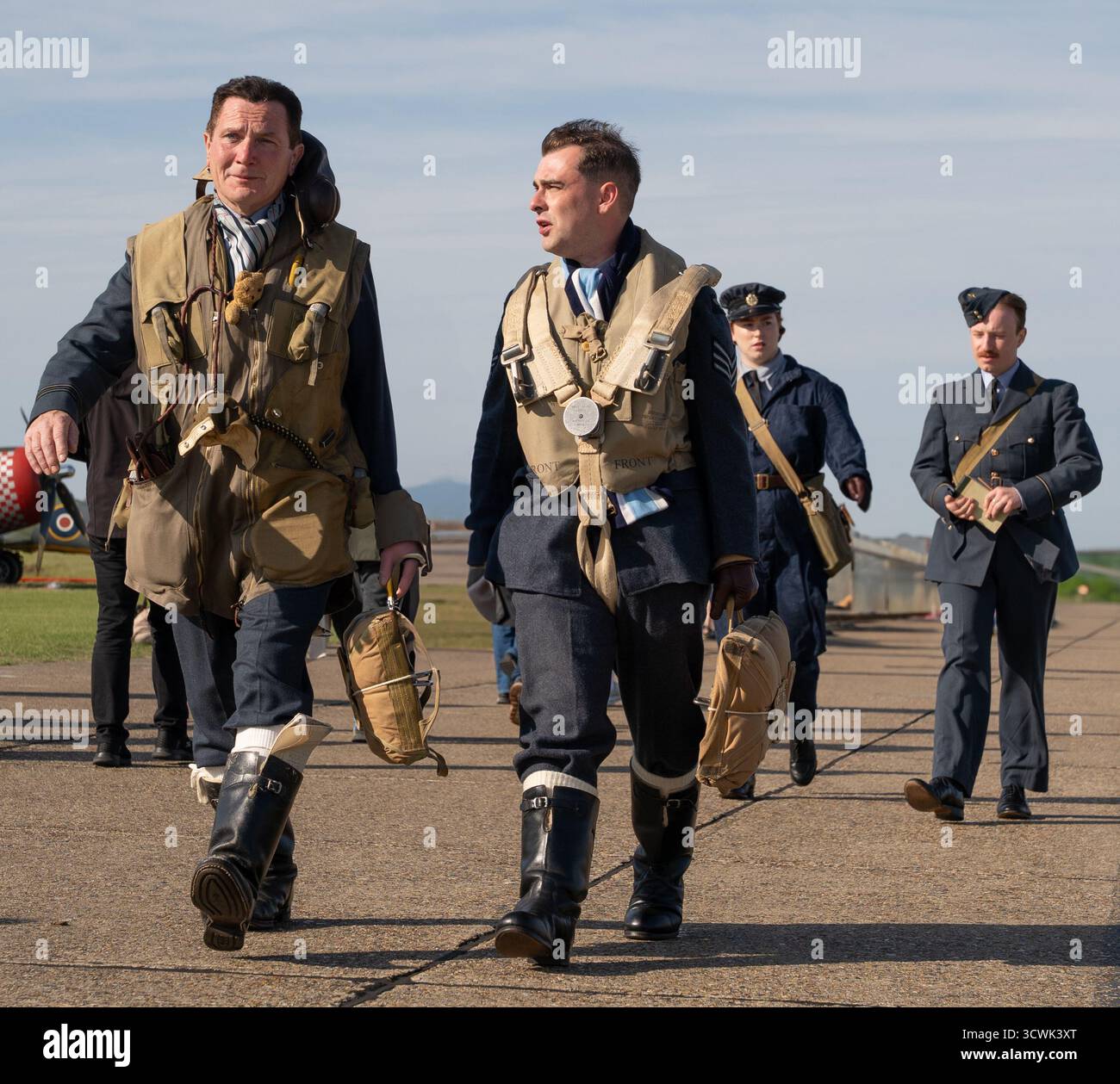 RAF aircrew and pilots walking across airfield at Duxford in vintage ...