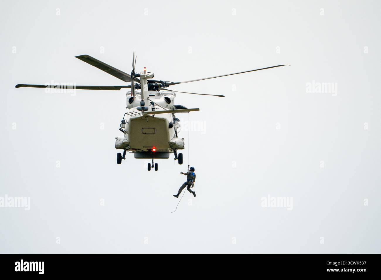 Military helicopter with person rappelling during training exercise at ...