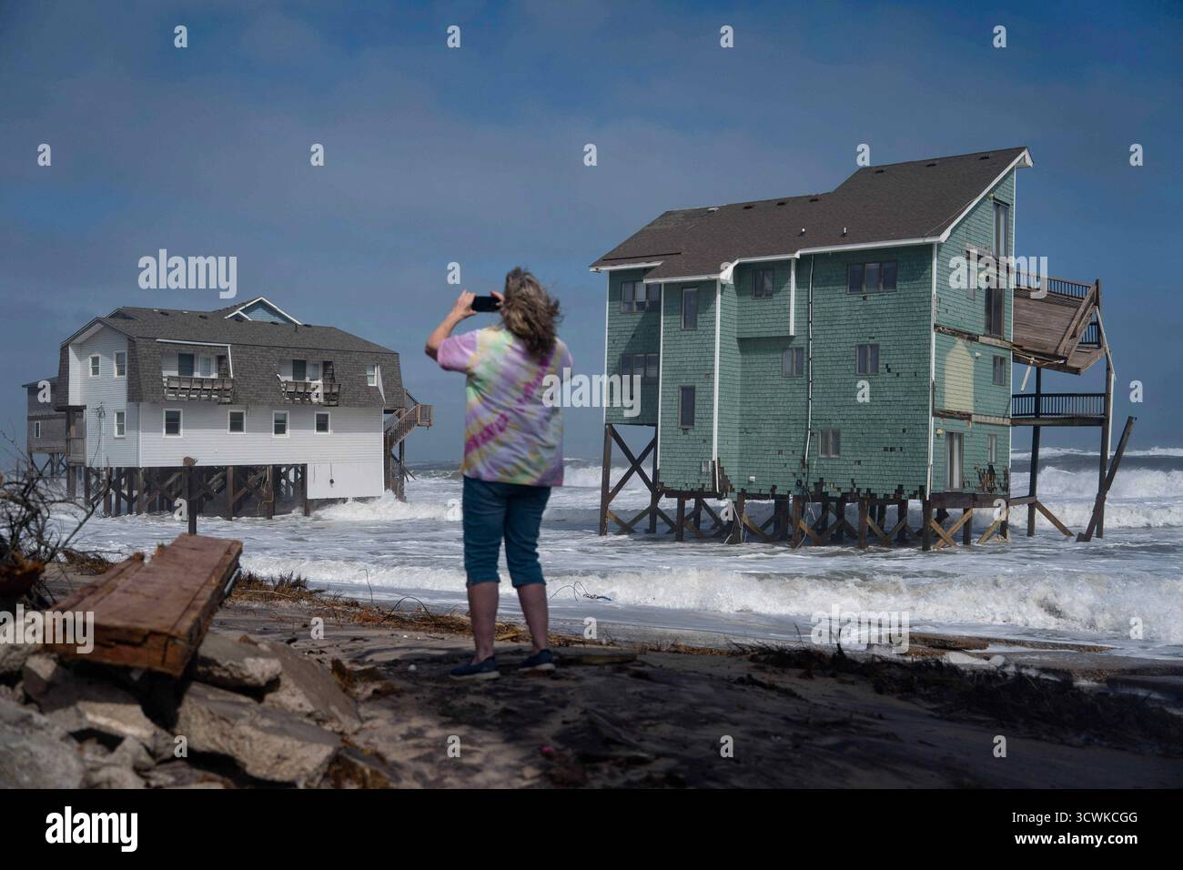 A person stands and takes photos of houses at risk of collapse in the ...