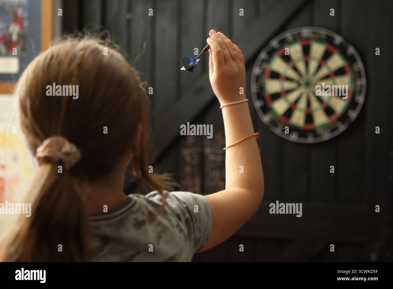 Girl throwing darts at dartboard in garage at home playing darts Stock ...