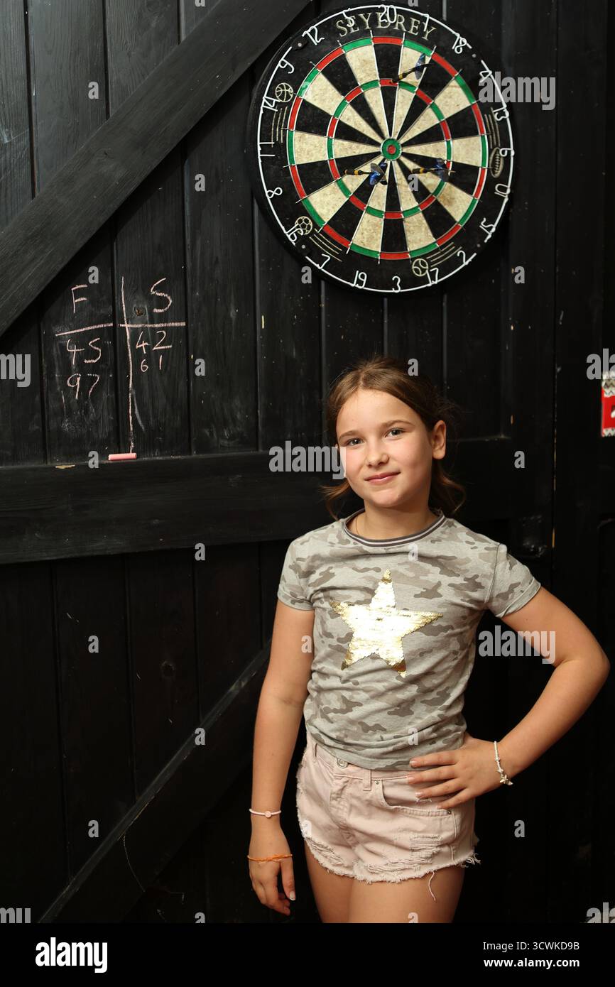 Girl standing under dartboard playing darts in garage at home Stock ...