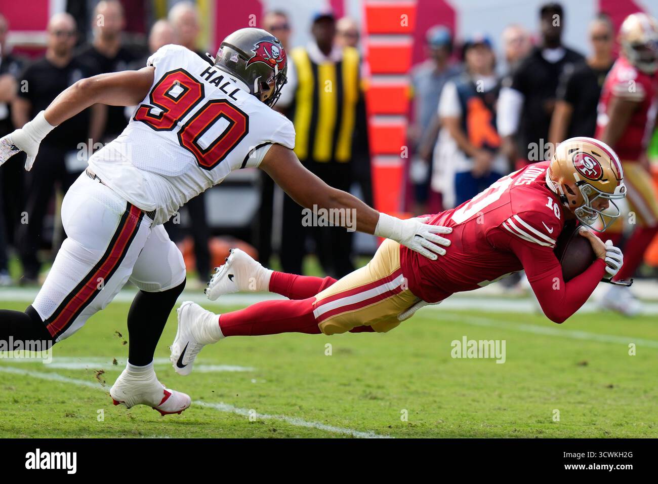 San Francisco 49ers quarterback Mac Jones, right, dives in front of Tampa Bay Buccaneers ...