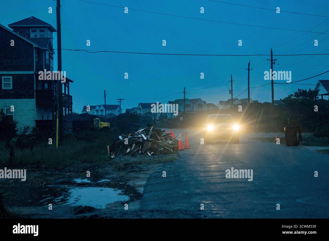 A car drives past a debris pile in the midst of a storm, Sunday, Oct ...