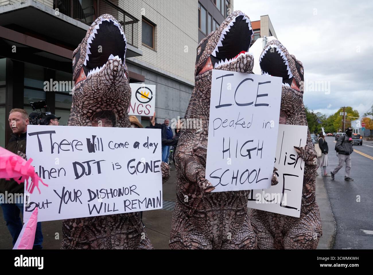 Demonstrators in inflatable dinosaur costumes hold signs in protest ...