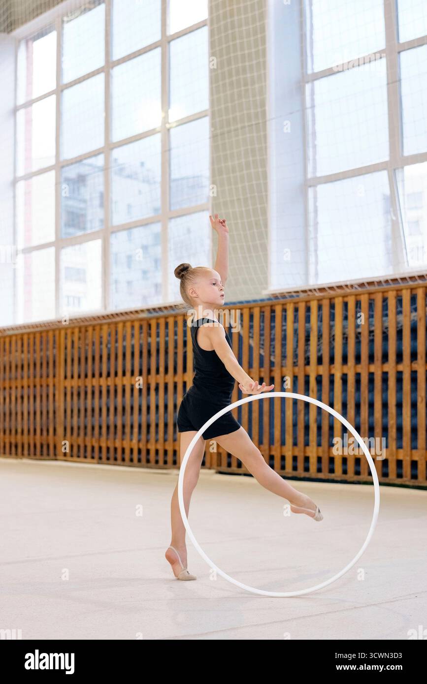 Caucasian girl performing rhythmic gymnastics routine with hoop ...