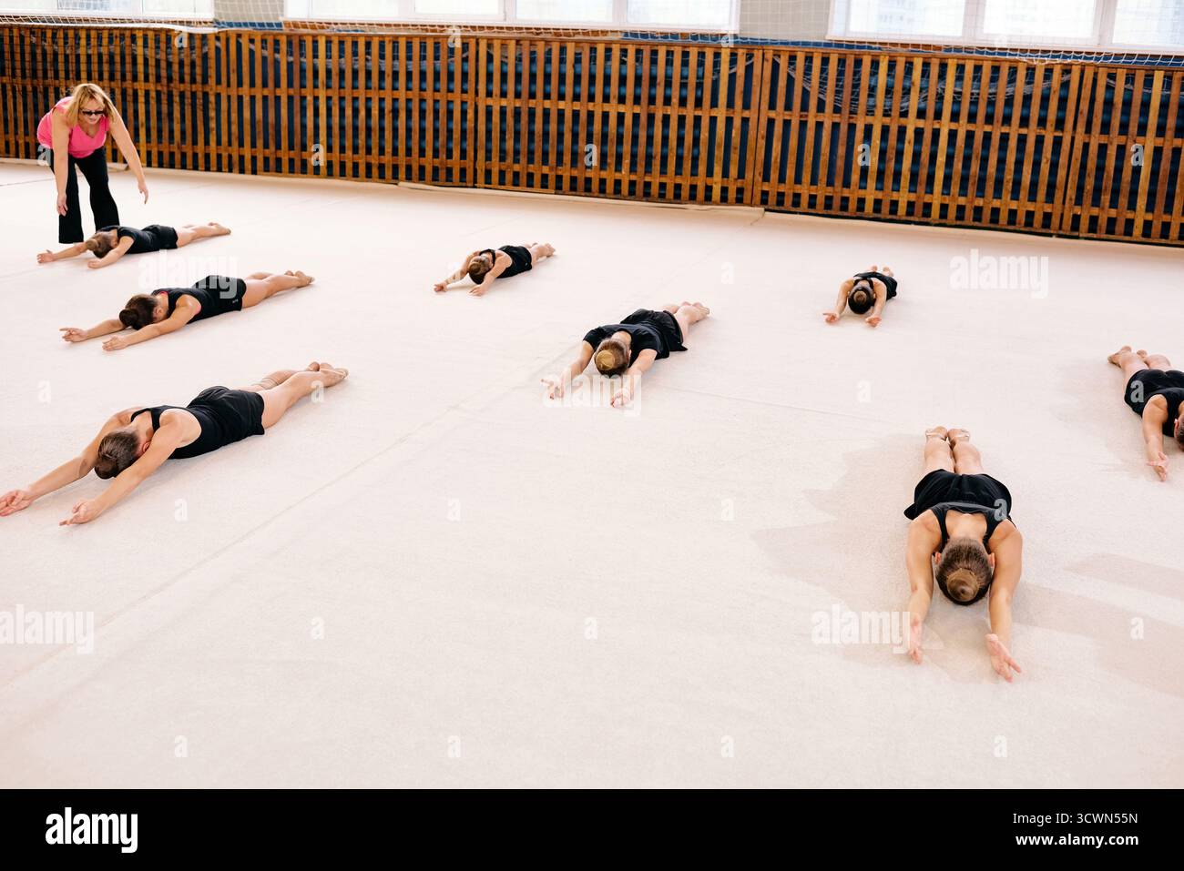 Group of Caucasian girls lying on gym floor stretching arms forward ...
