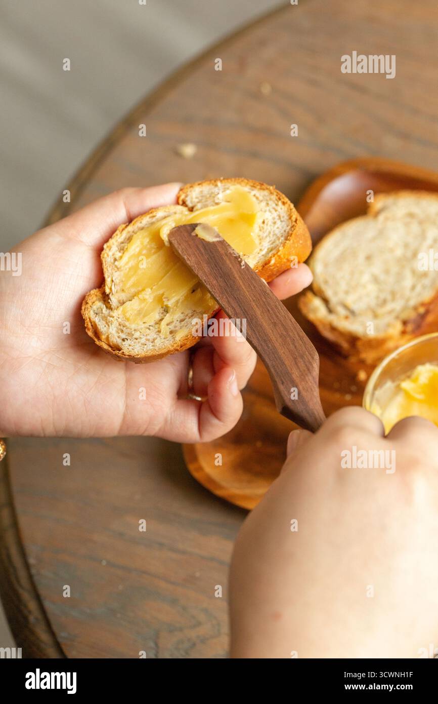 Spreading golden butter on a fresh piece of bread, Woman's hands ...