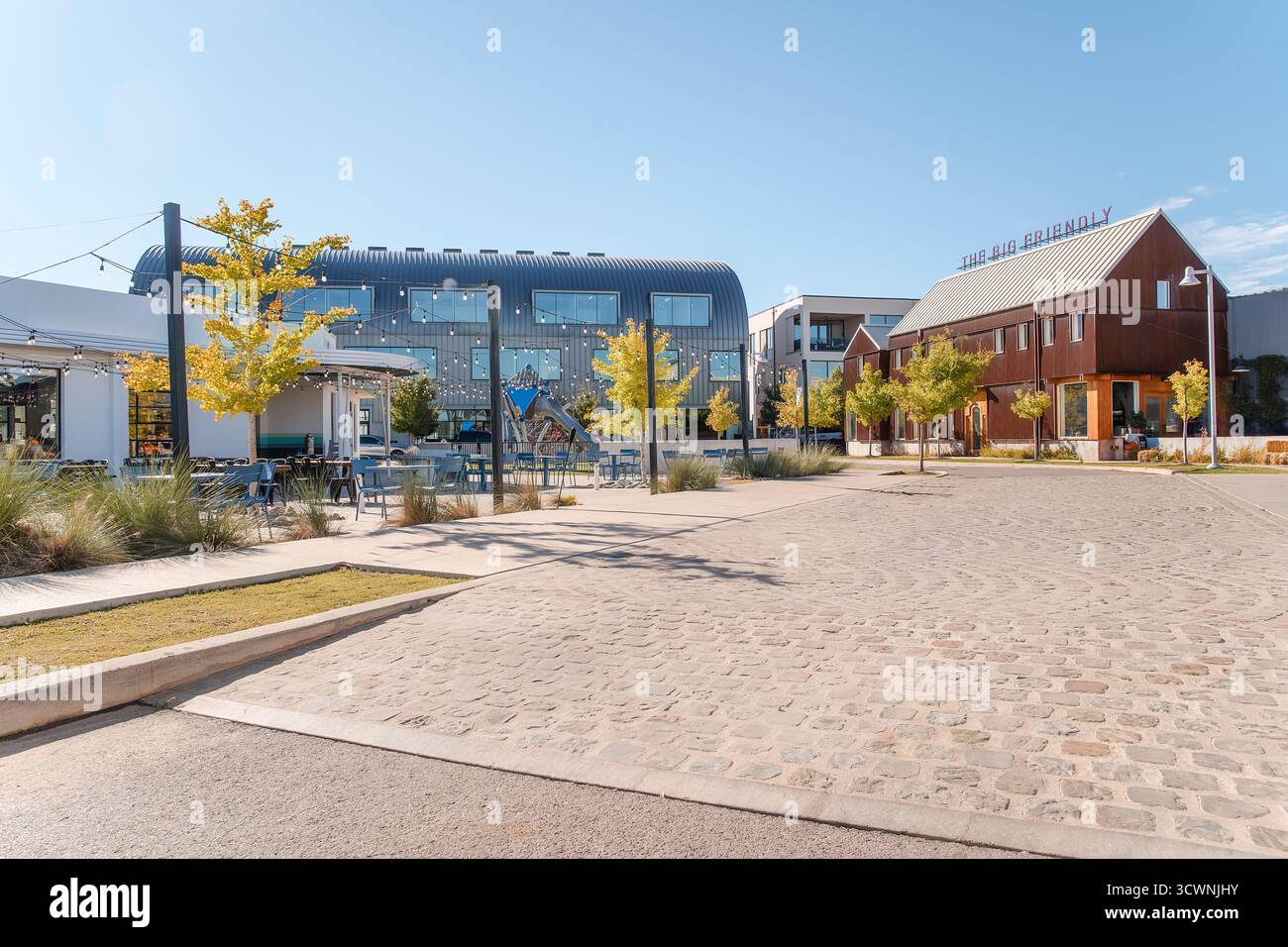 Modern plaza with rounded buildings, shops, and outdoor seating area ...