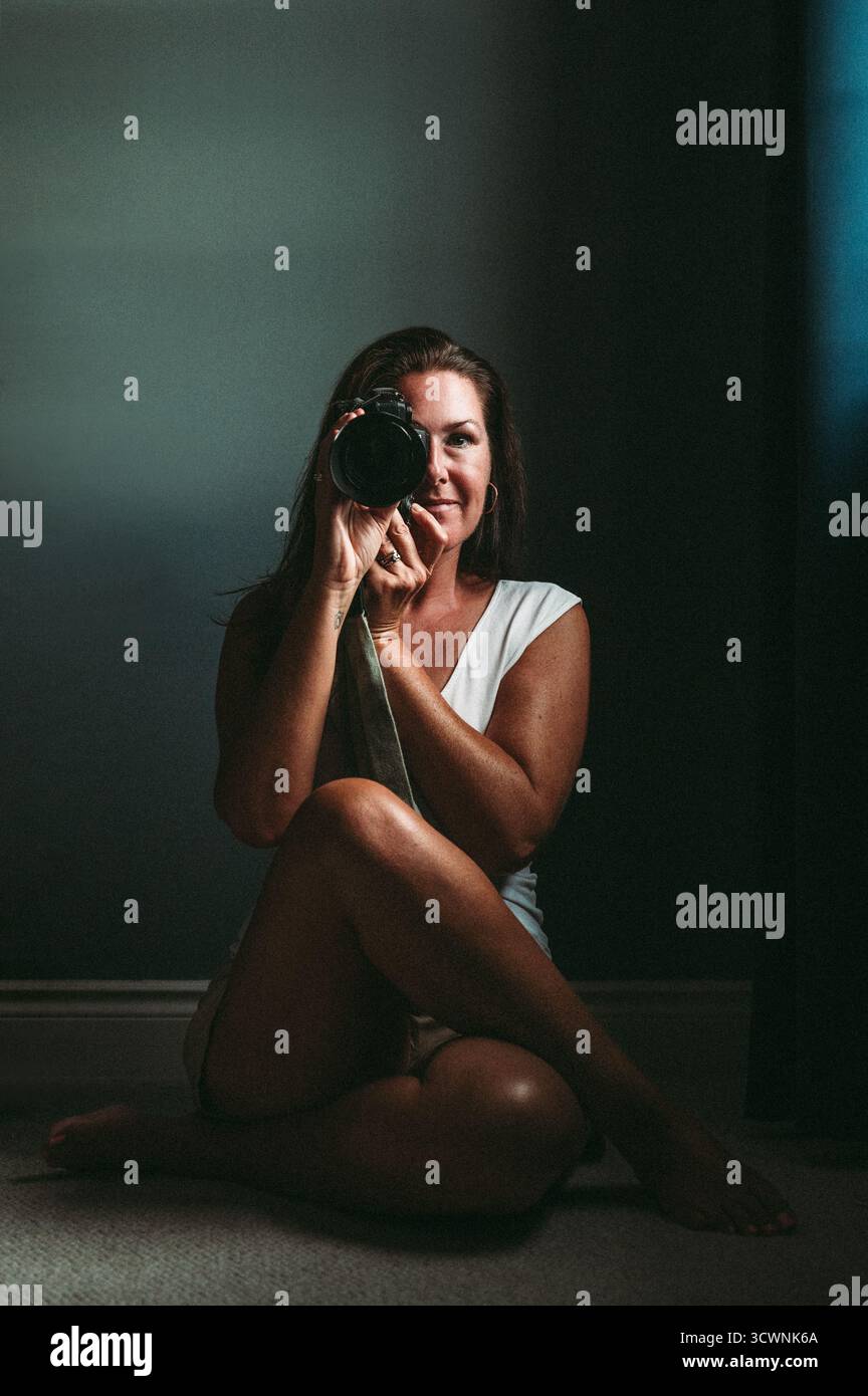 Woman photographer in dark room looking through camera Stock Photo - Alamy