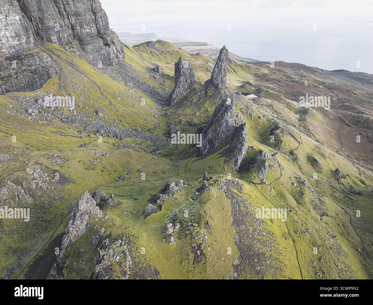 Aerial view of jagged cliffs rise from a mossy, green landscape ...