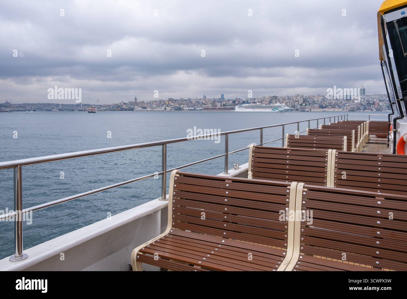 Wooden benches on the deck of a ferry boat with the city of Istanbul ...