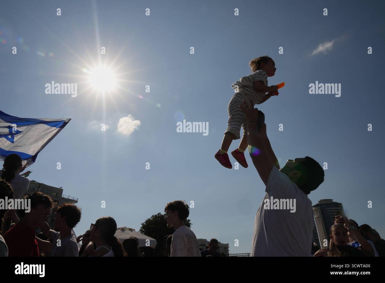 A man lifts a child in the air as people celebrate the arrival of freed ...
