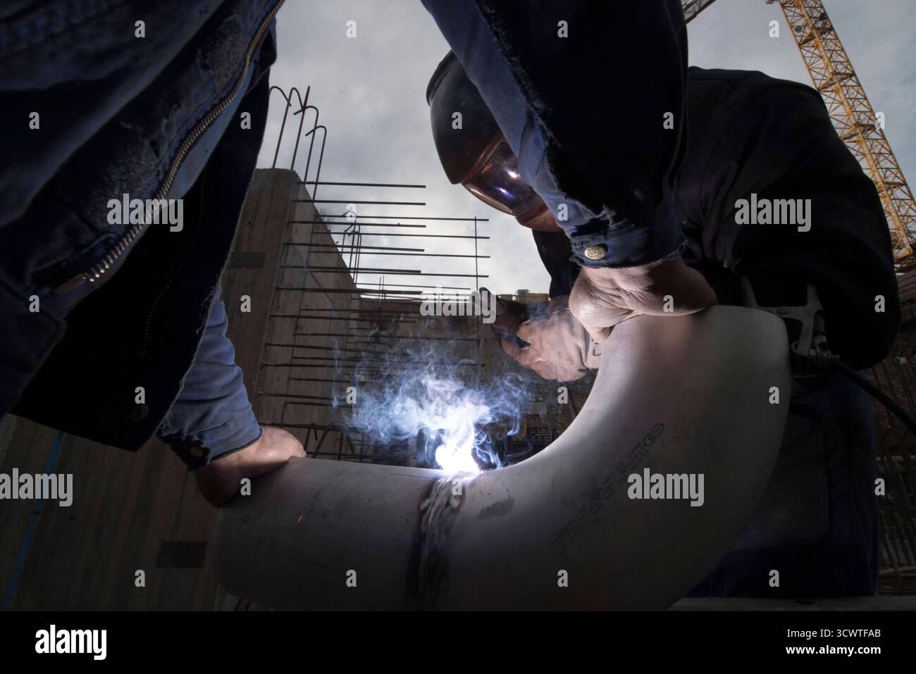 a metal worker is welding a pipe in protective clothing worker welding ...