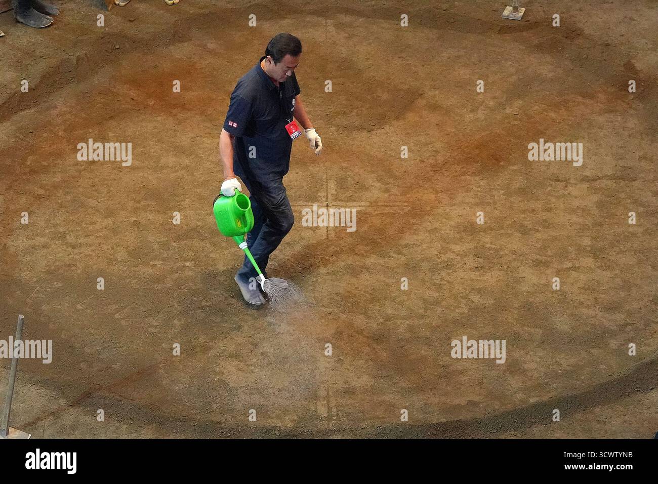 A worker waters the surface to build up the dohyo, the sacred sumo ...