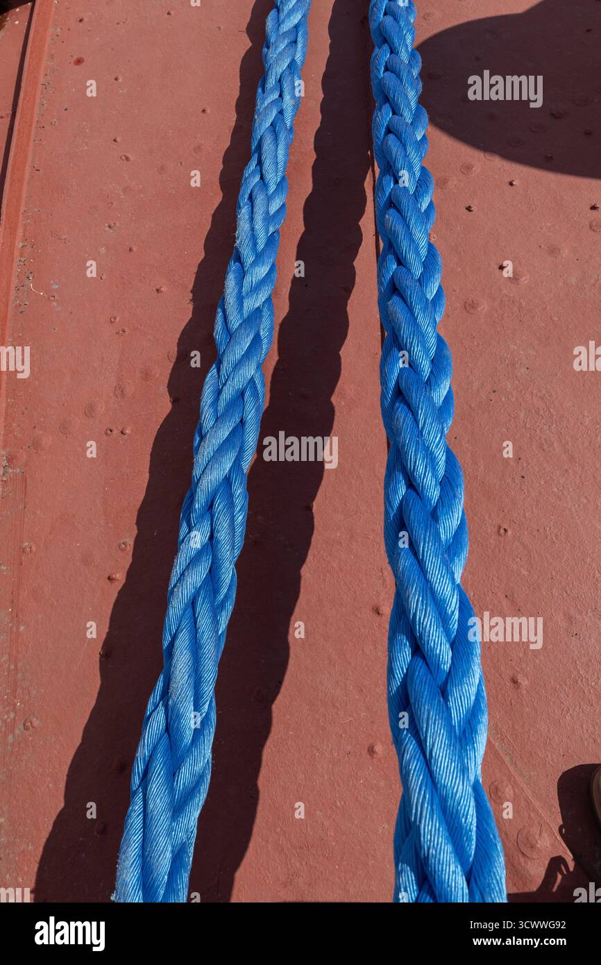 Thick and strong heavy duty blue mooring ropes against ship's metal ...