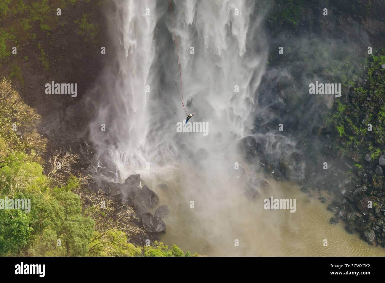 A view of Cascata do Caracol waterfall and person bungee jumping at ...