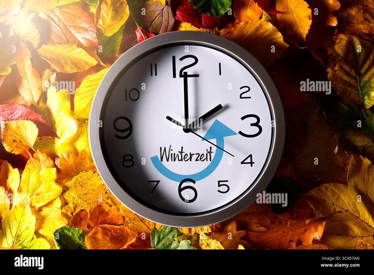 FOTOMONTAGE, Uhr auf Herbstblättern mit Pfeil und Aufschrift Winterzeit ...