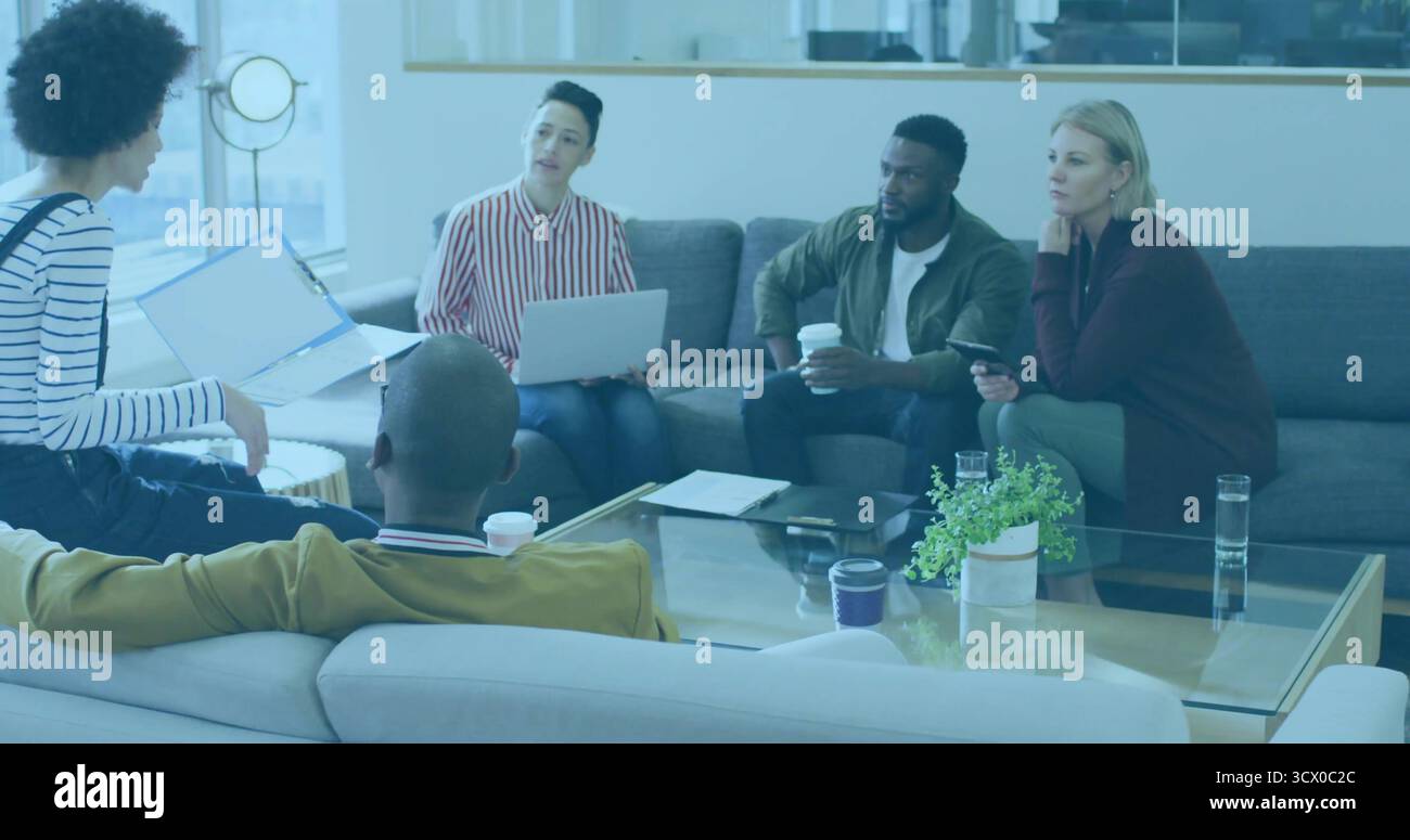 Five professionals sitting around coffee table in lounge with notebooks ...