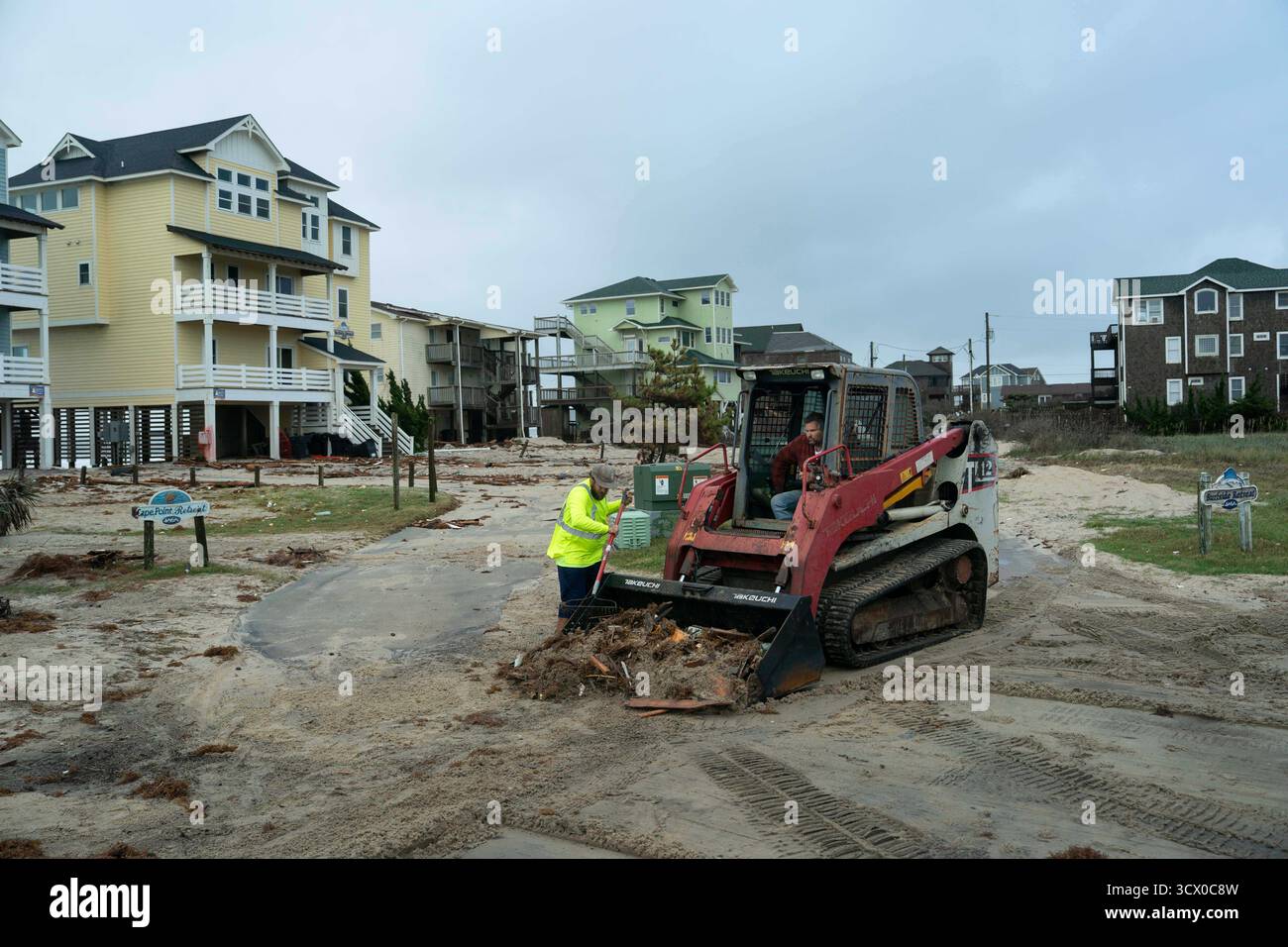 Barry Crum sits in a skid-steer while Luke Powell loads debris after a ...