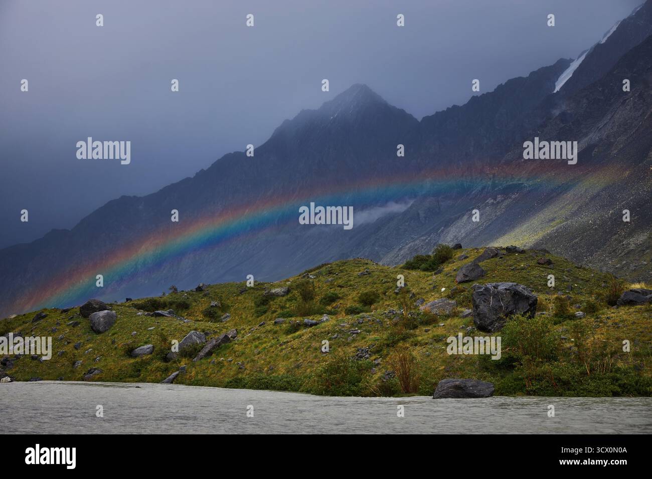 vibrant rainbow stretches across the sky, bridging the mountains and ...