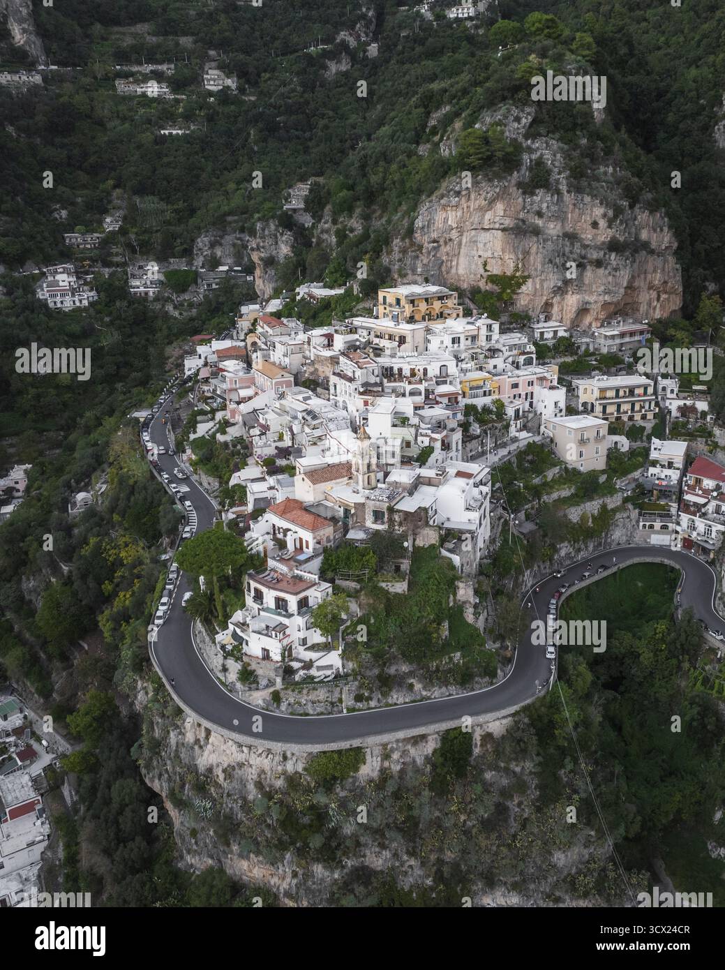 Aerial view of white buildings cascading down the cliffside, a winding ...