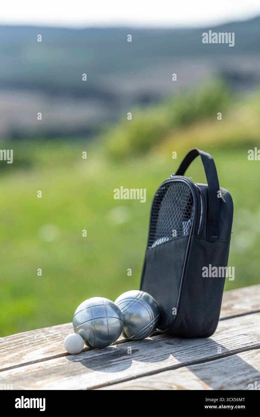 Petanque boules and cochonnet resting on a wood table, enjoying outdoor ...