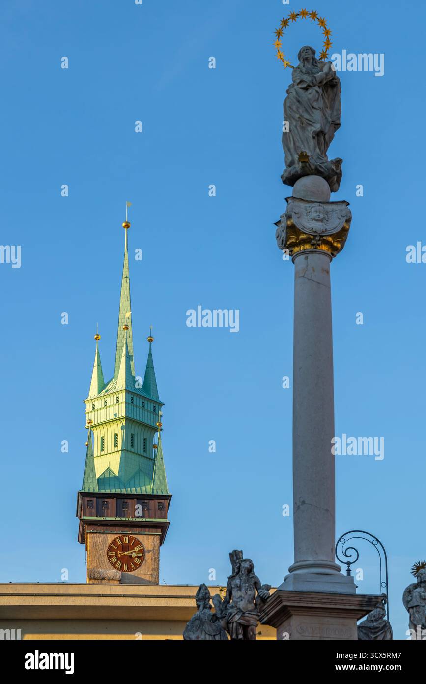 Virgin Mary statue on plague column with historic town hall clock tower ...