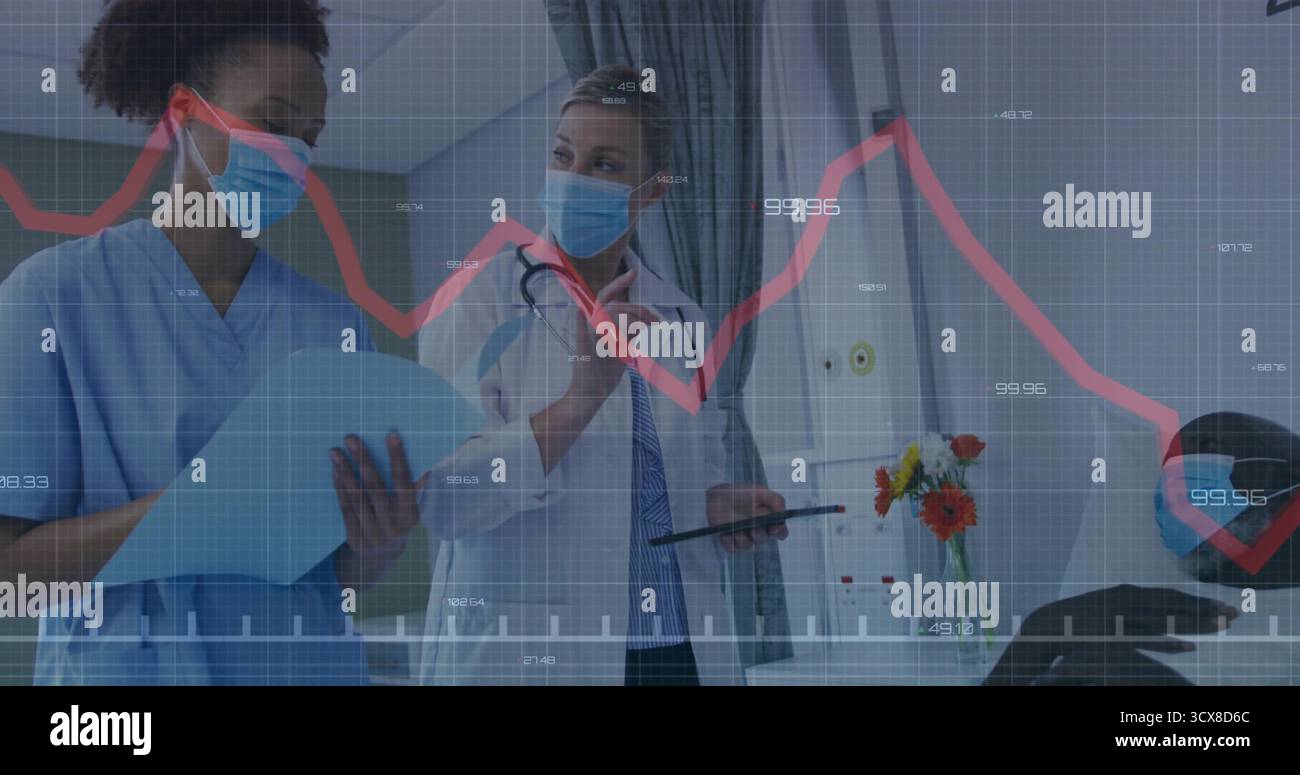 Reviewing scrub-clad nurse and doctor pointing at tablet at bedside ...