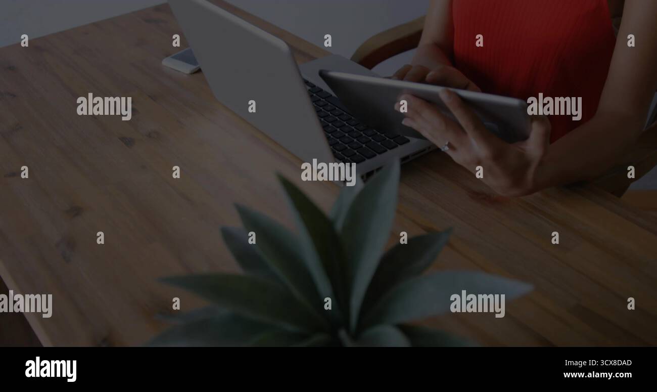 Tapping tablet device woman wearing red top at wooden desk, smartphone ...