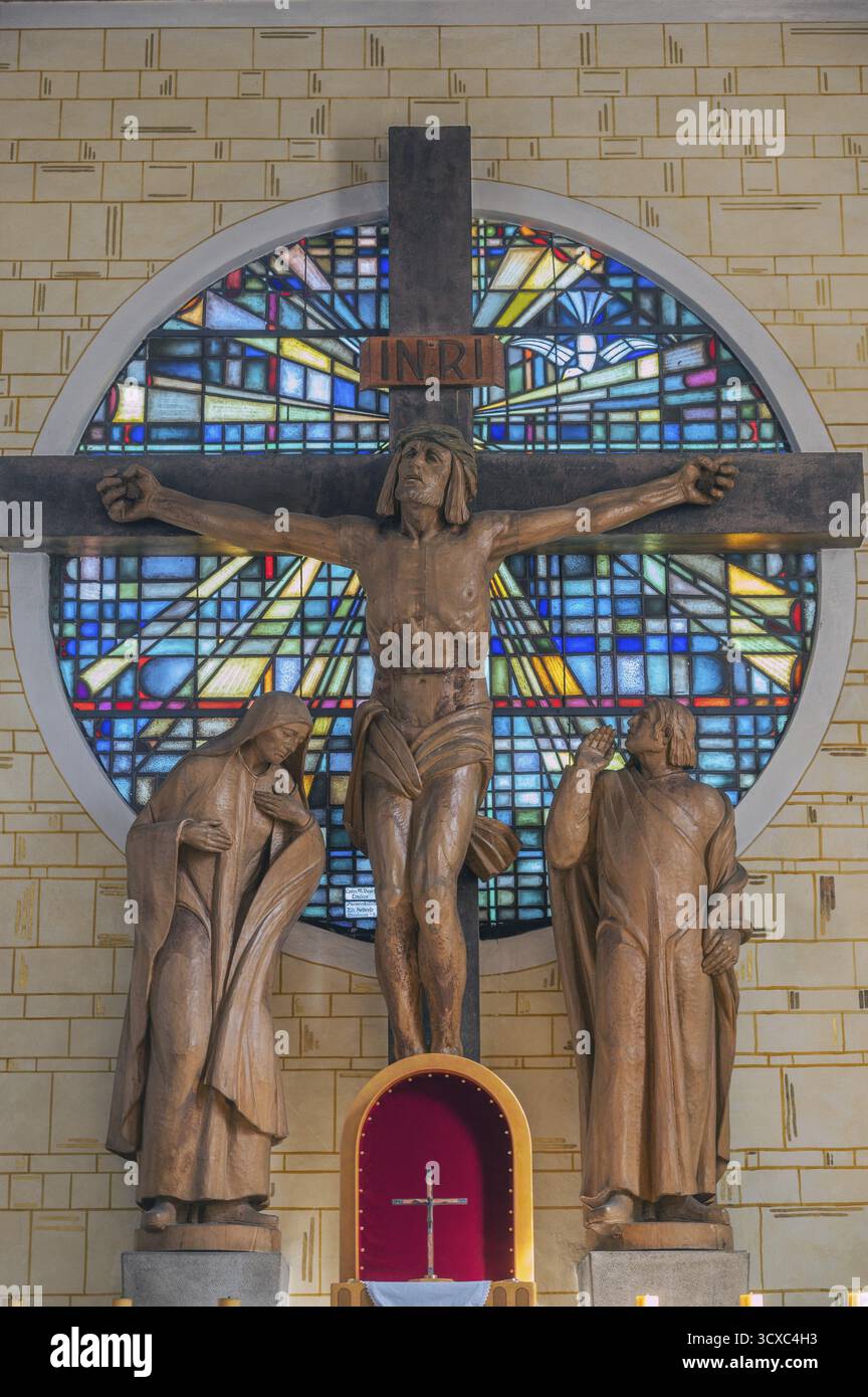 Main altar with crucifix, colourful stained glass window and figures of ...