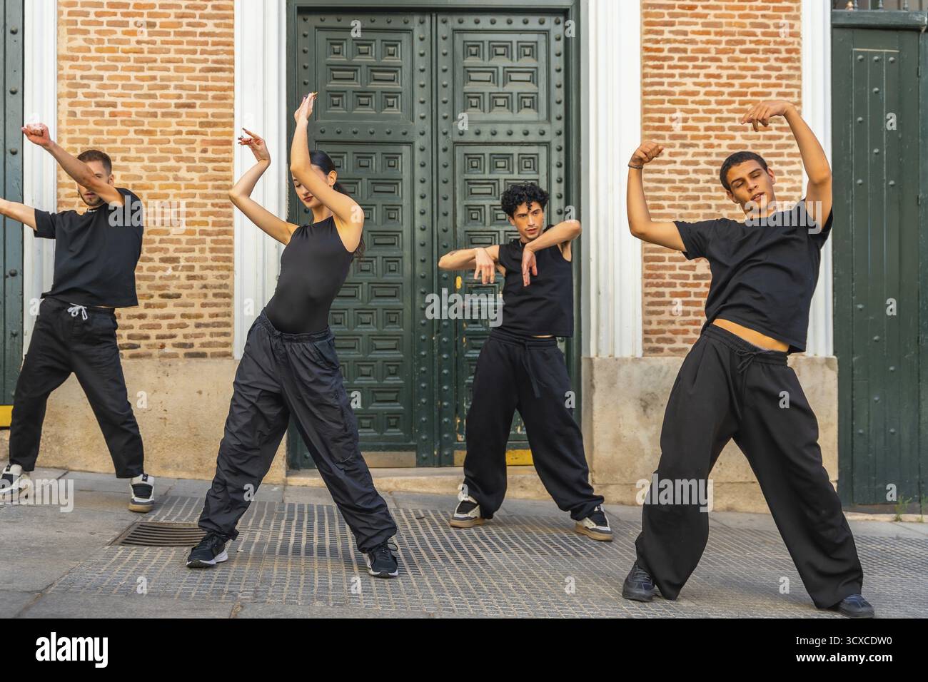 Four young male and female dancers dressed in black performing a modern ...
