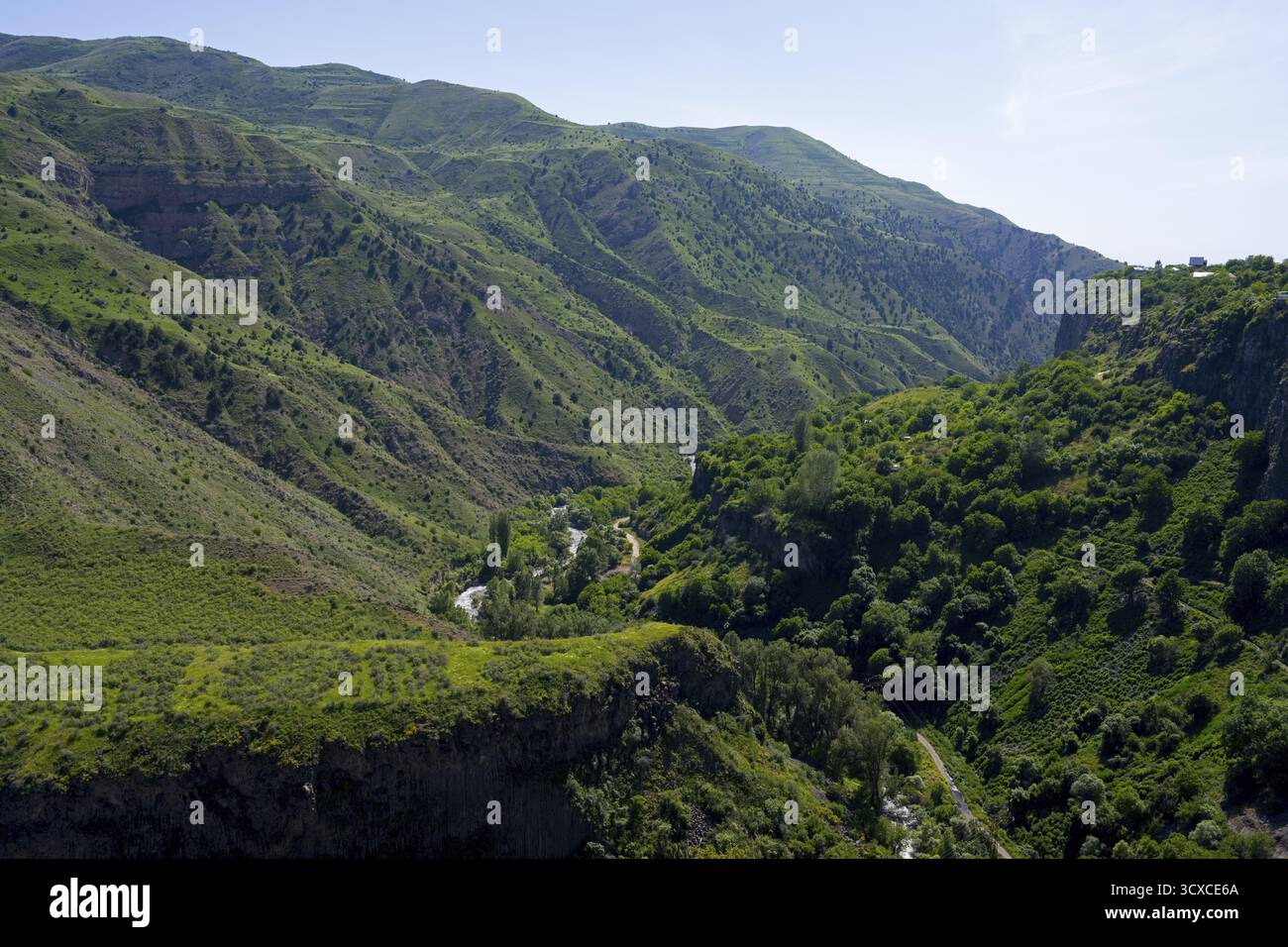 Deep gorge with dense green vegetation and wooded slopes under a clear ...