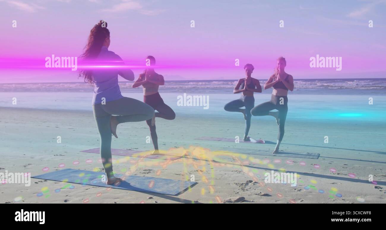 Balancing four yogis holding tree pose on sandy beach at water's edge ...