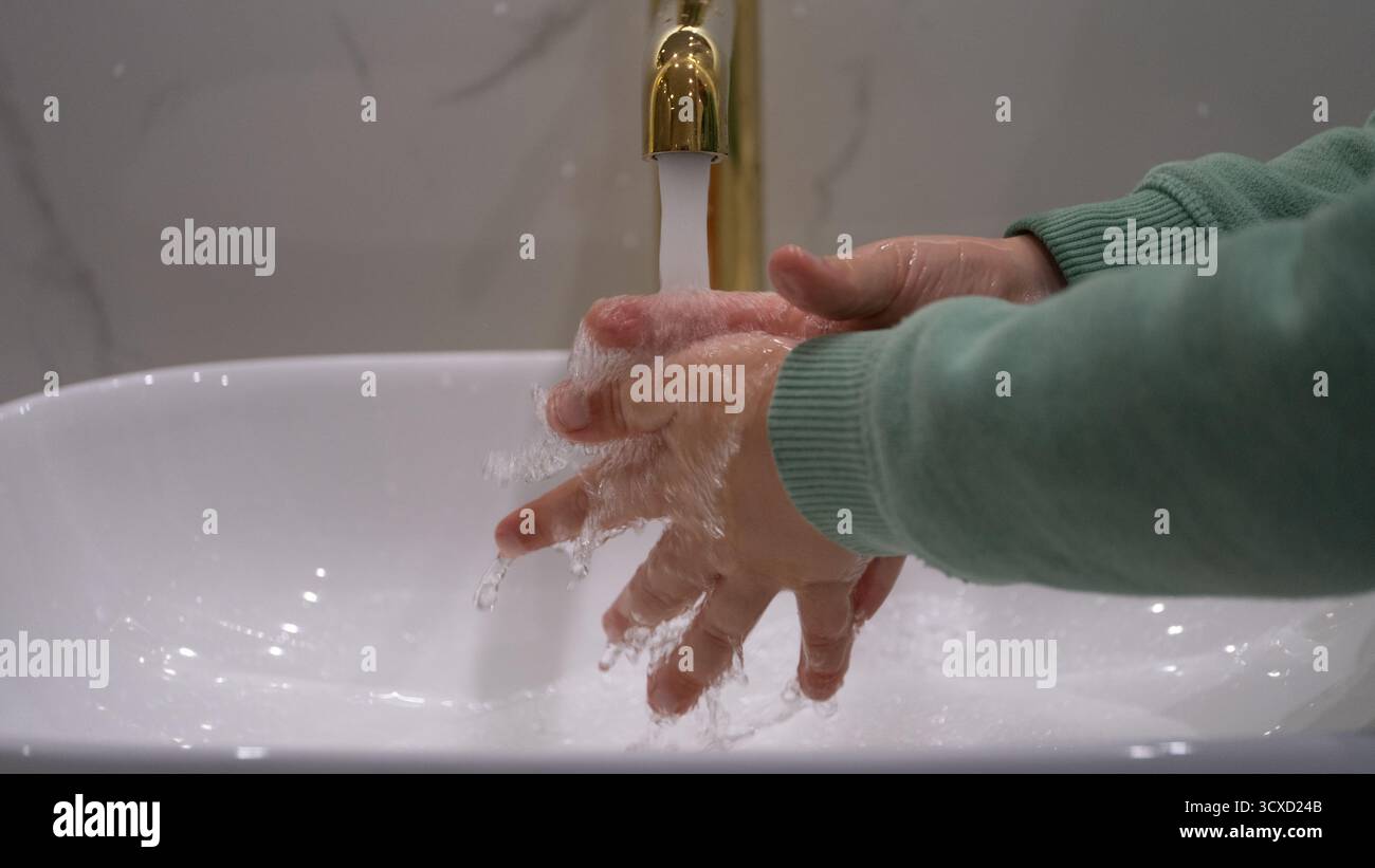 Close-up of child washing hands under running tap water. Real and ...