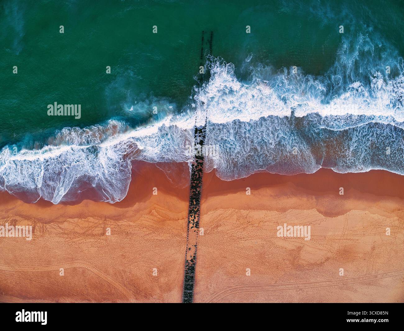 Aerial view of the wooden groyne dividing the turquoise water and the ...