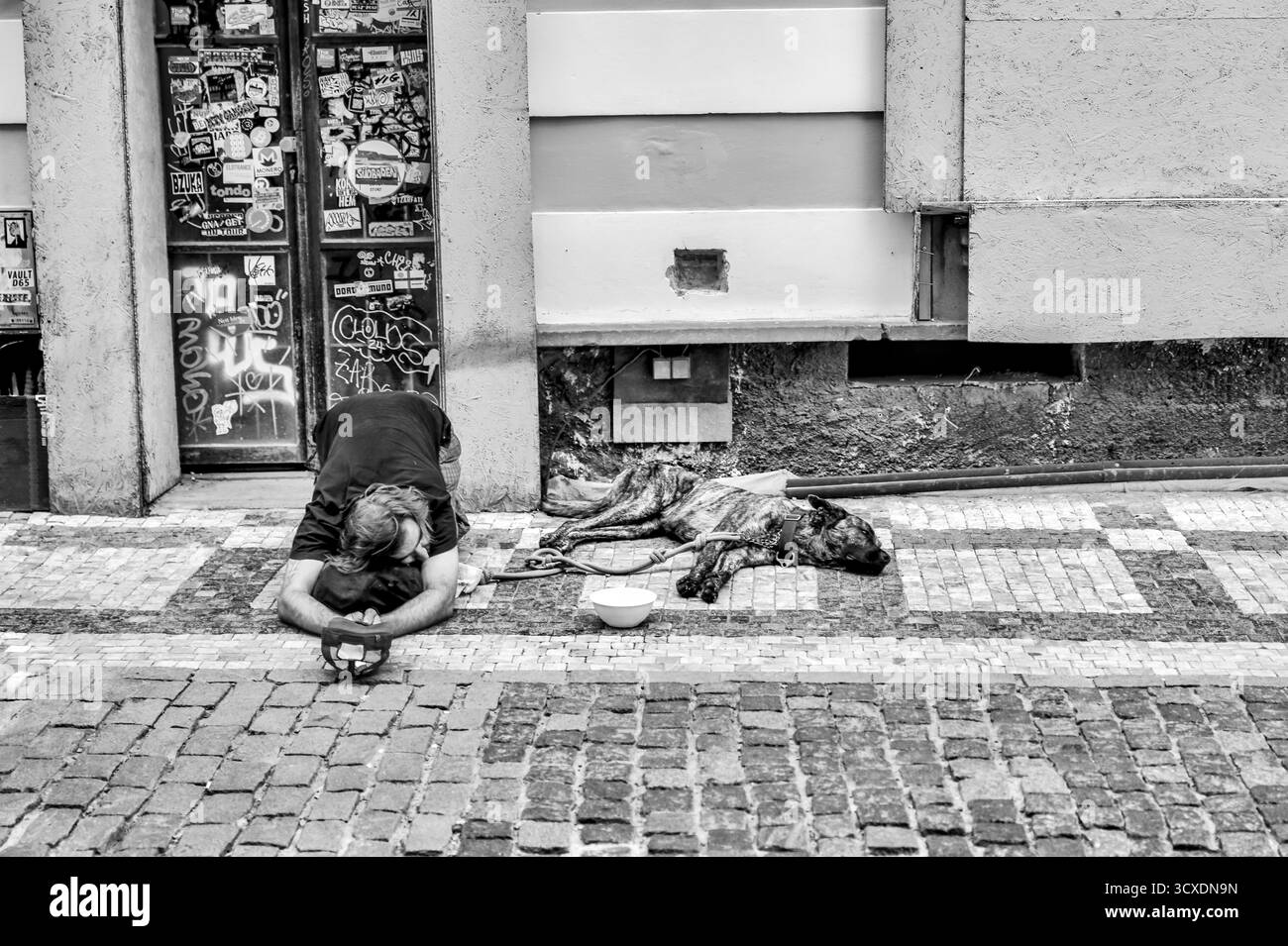 A man begging for change alongside his dog on the streets in Prague in ...