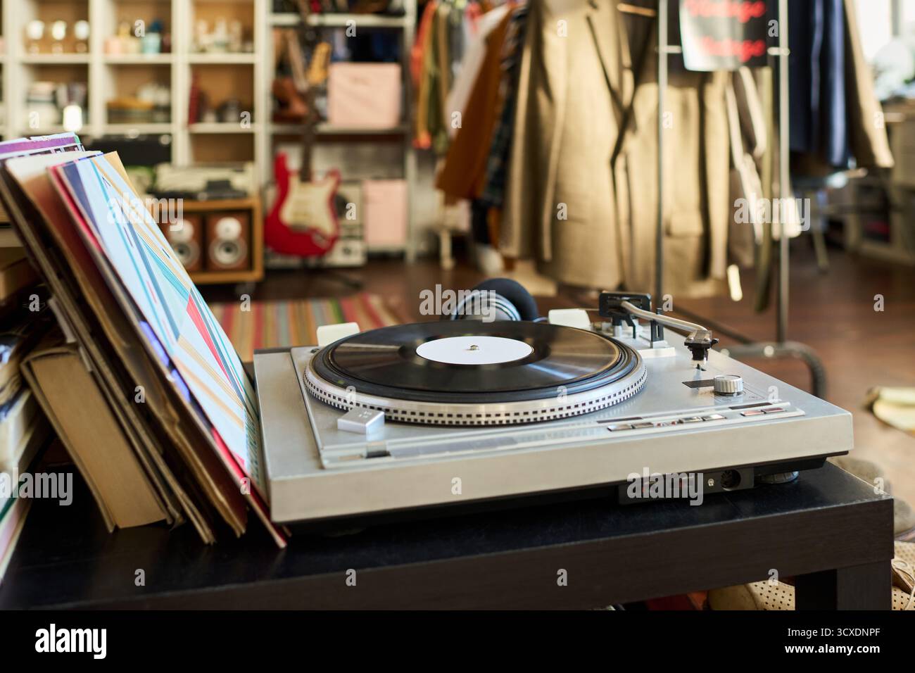 Vintage turntable playing vinyl record on table surrounded by stacks of ...