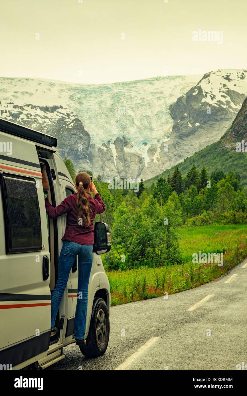 Woman in a campervan taking a photo of the dramatic Bergsetbreen ...