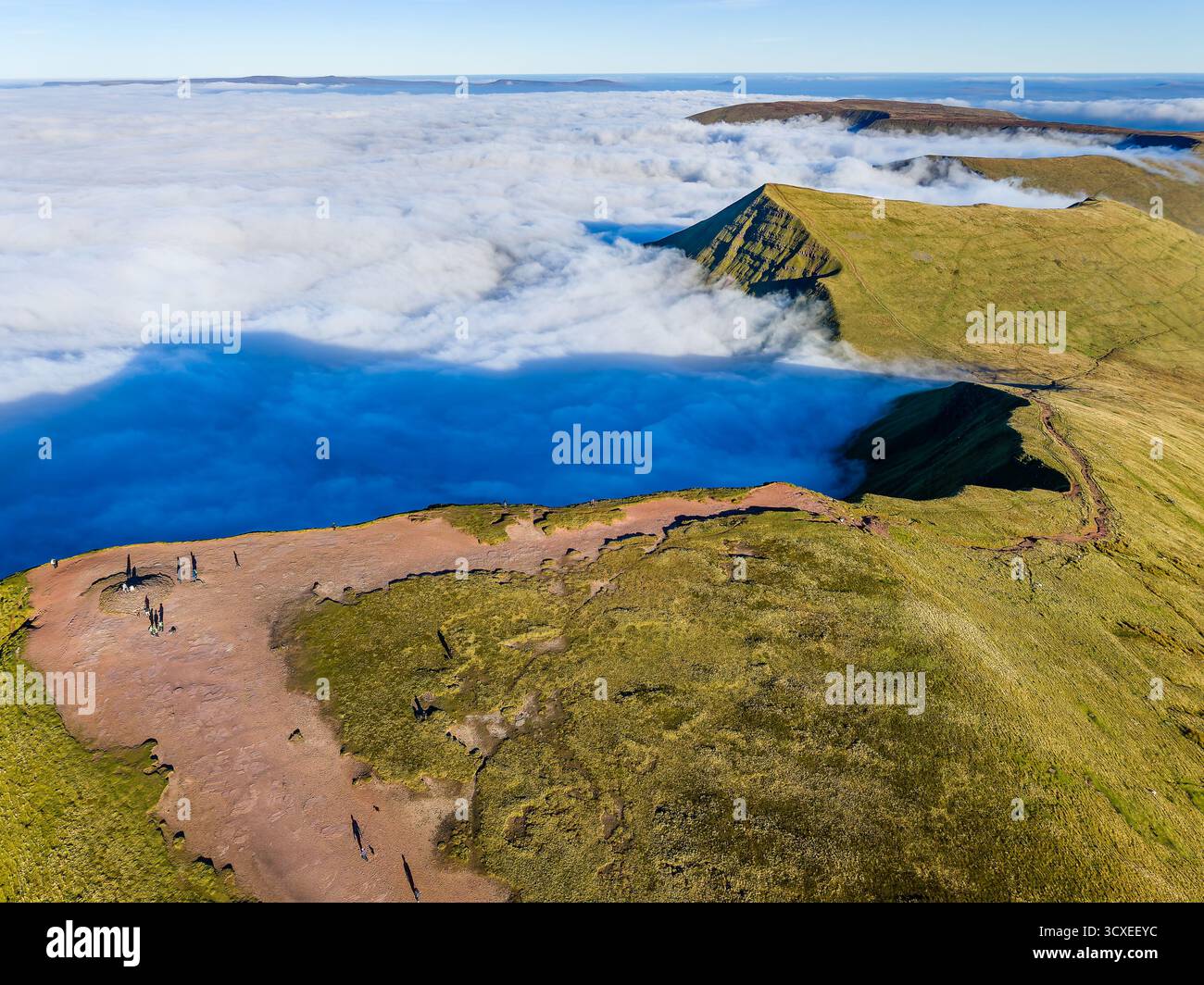 Hikers on a mountain summit looking out over a stunning cloud inversion ...