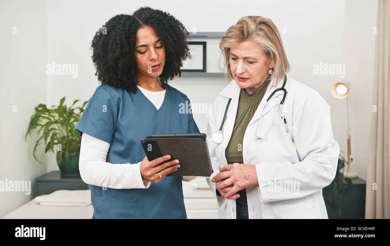 Nurse And Doctor Review Tablet Data Together In Clinic Office Setting ...