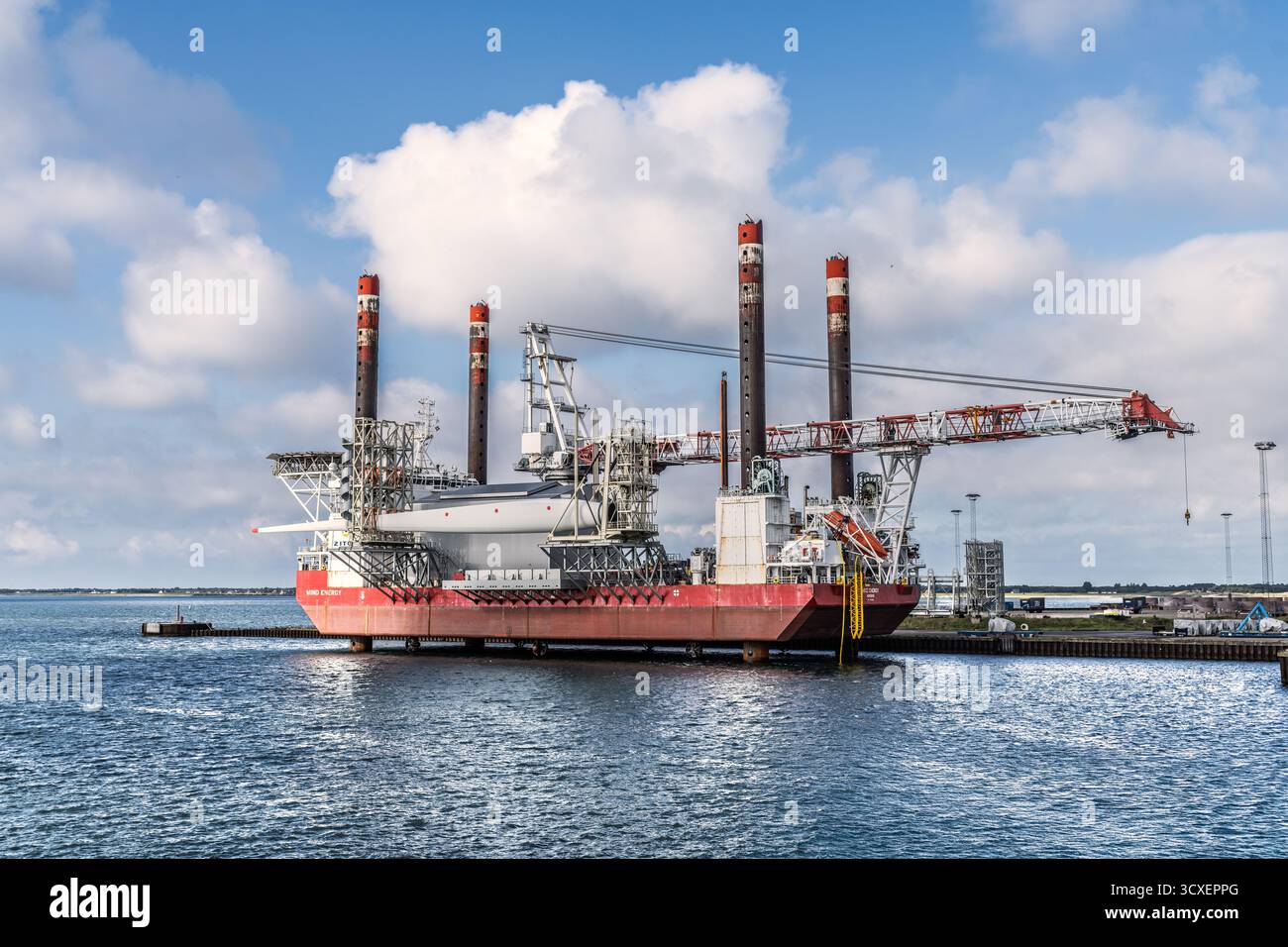 A large industrial cargo barge sits at the quay with a towering crane ...