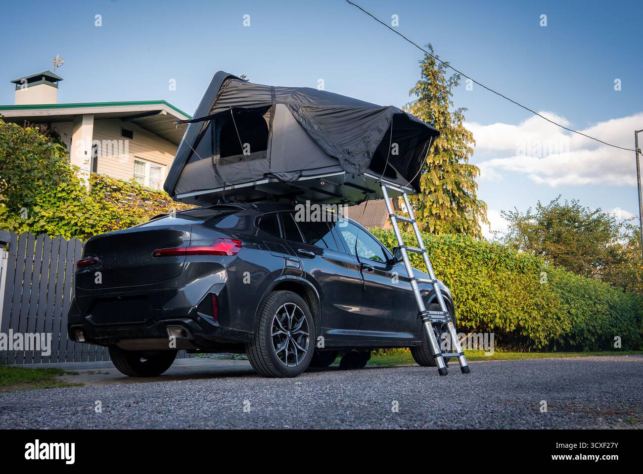 Black luxury SUV with rooftop tent on quiet suburban street Stock Photo ...